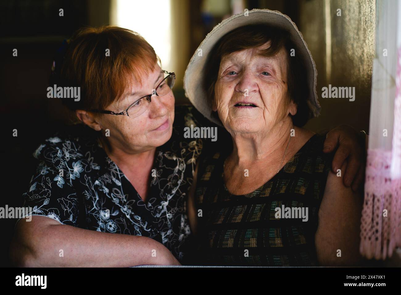 An older woman and her adult daughter sit together, their expressions ...