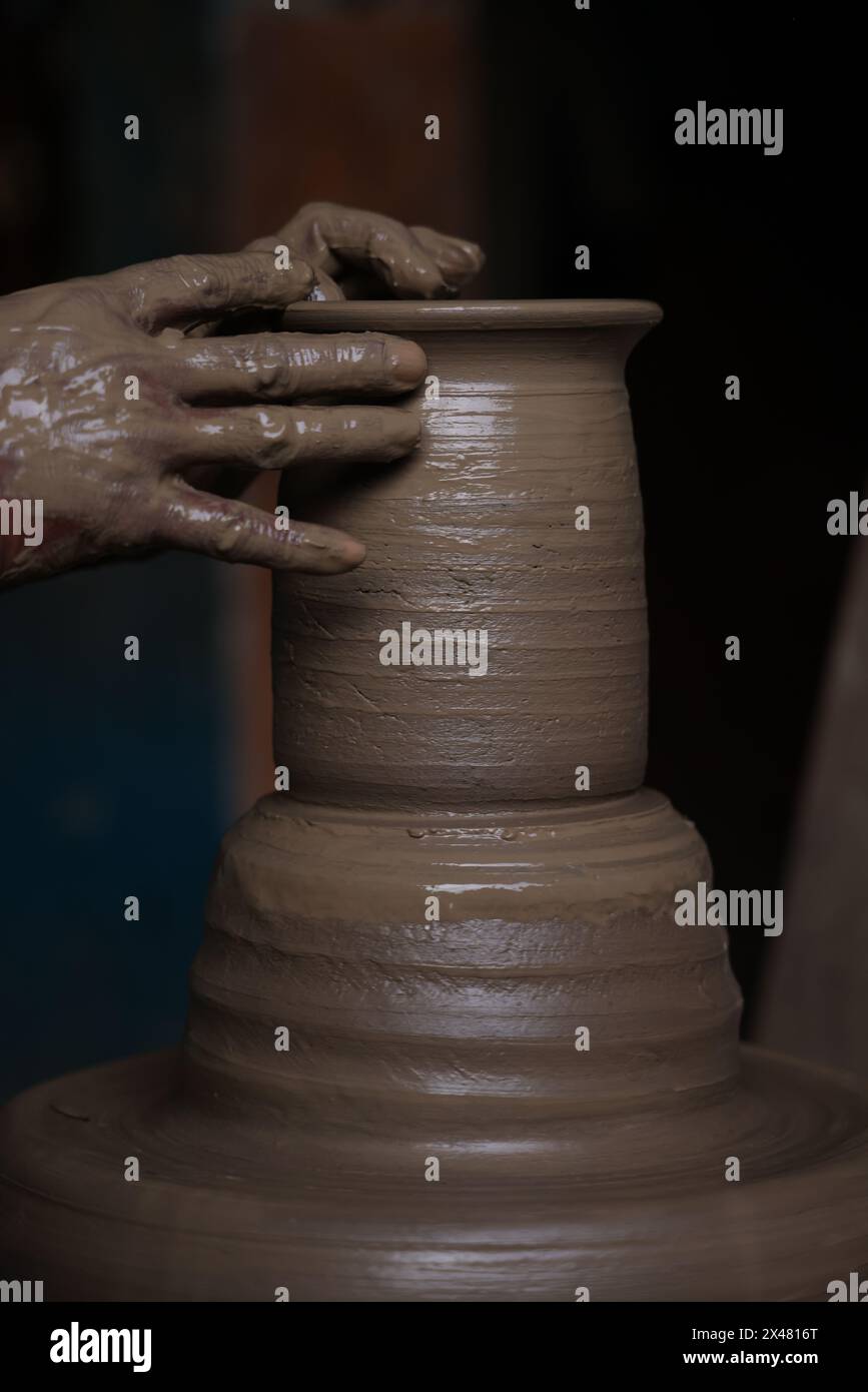 The potter works on a pottery wheel to made of soft colored clay, retro ...