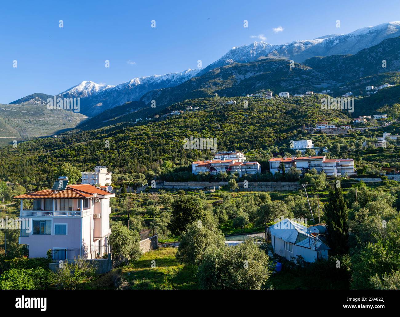 Snow capped peaks including Mount Cika rising above hillside village ...