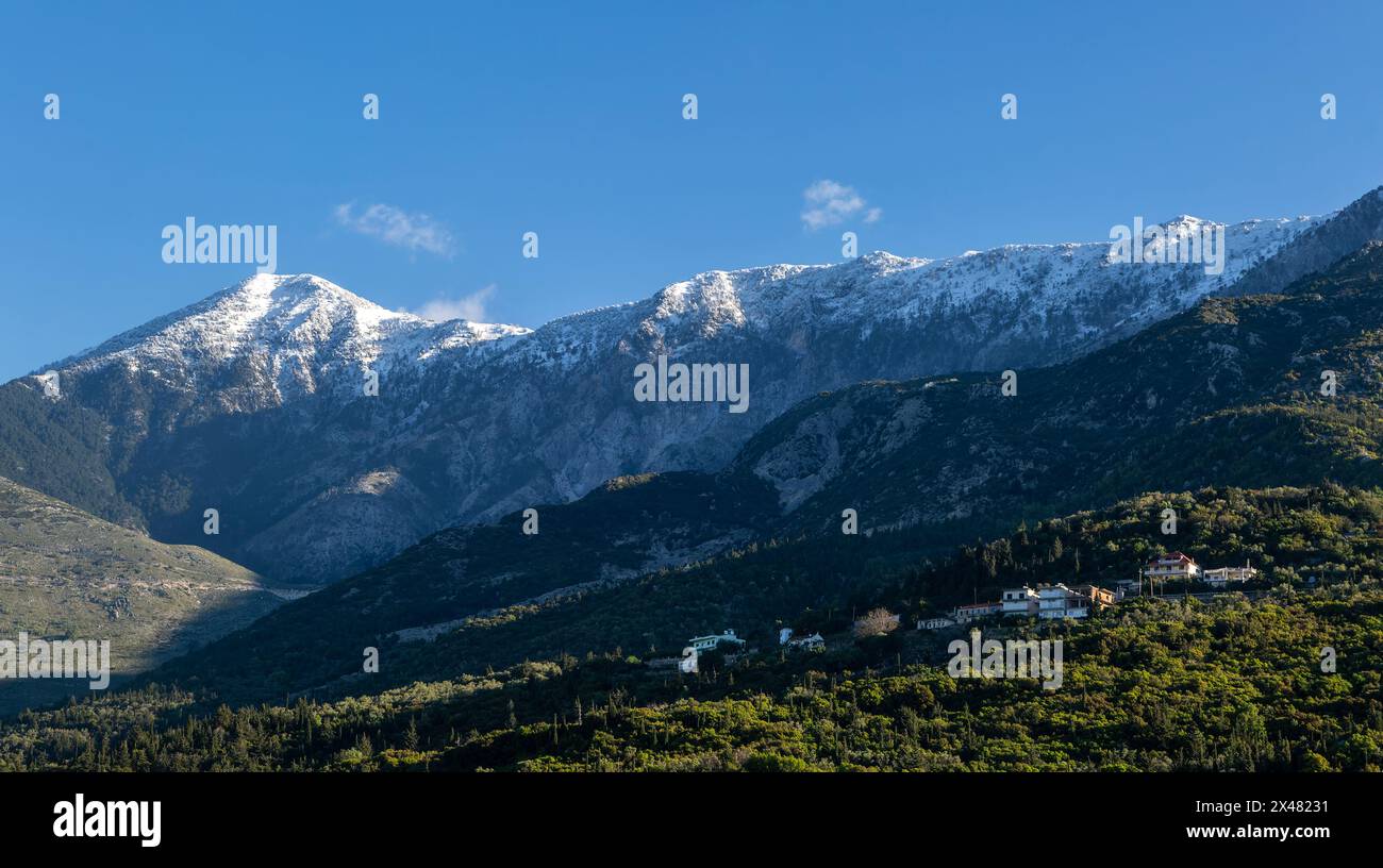 Snow capped peaks including Mount Cika rising above hillside village ...