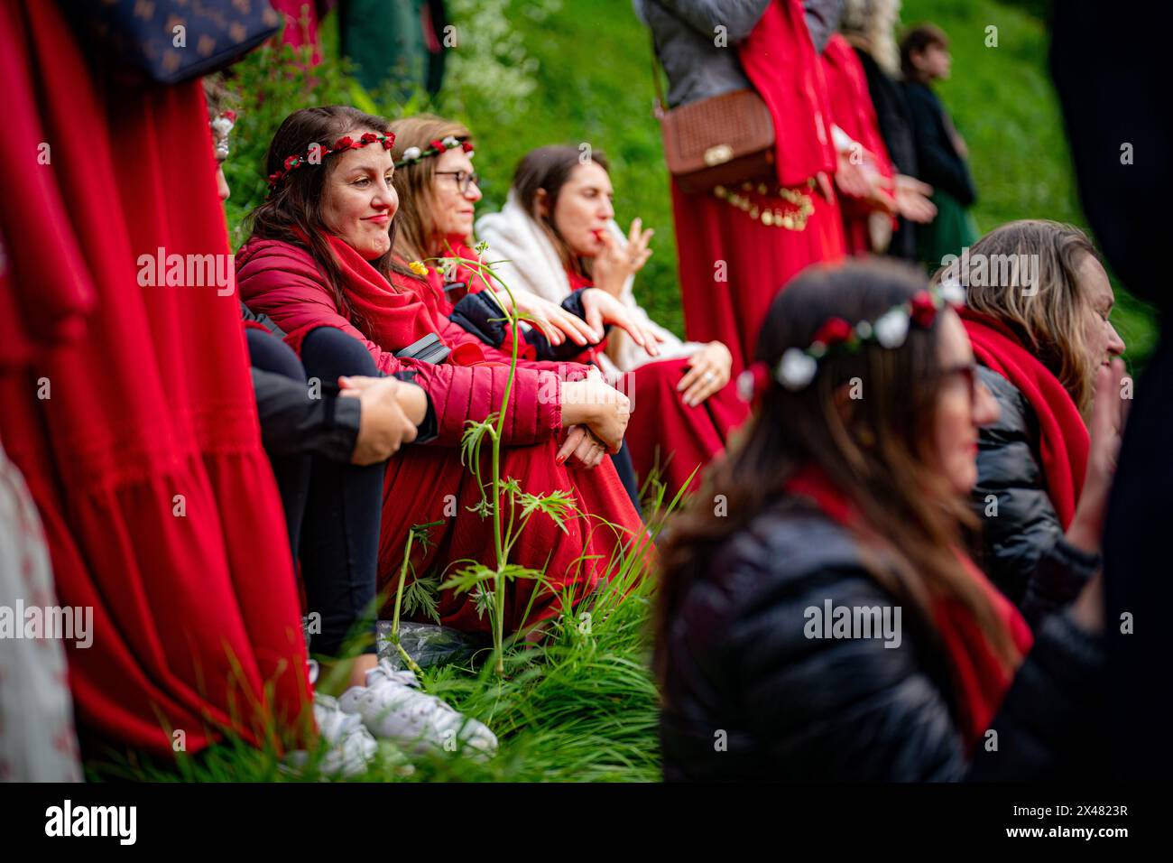 People sit on wet grass as they watch the Beltane celebrations at ...