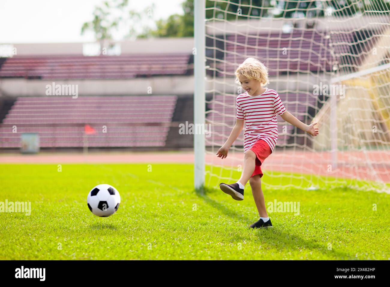 Kids play football on outdoor stadium field. Children score a goal ...