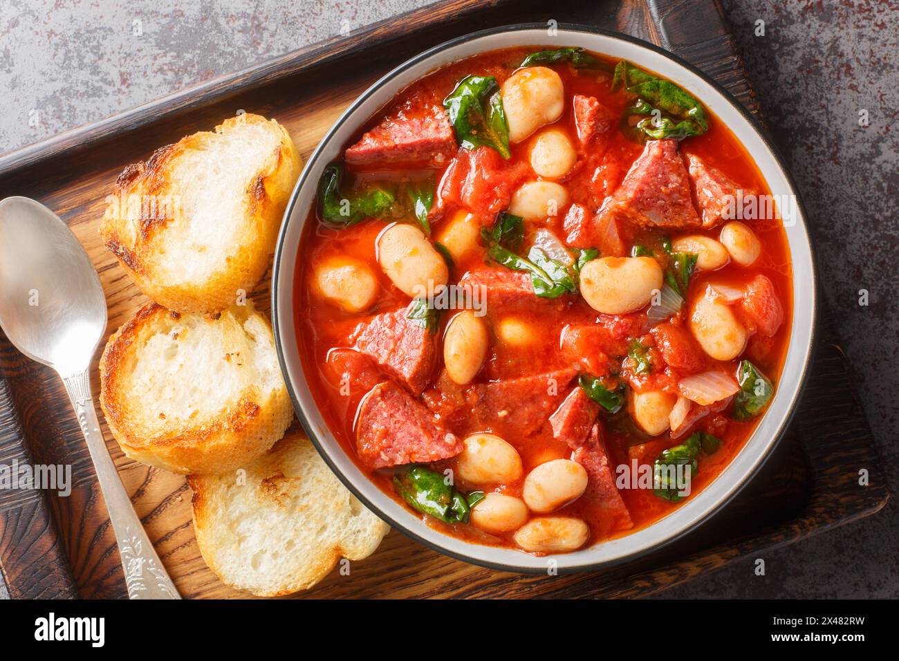 Spanish stew of butter beans, chorizo and spinach in tomato sauce close ...