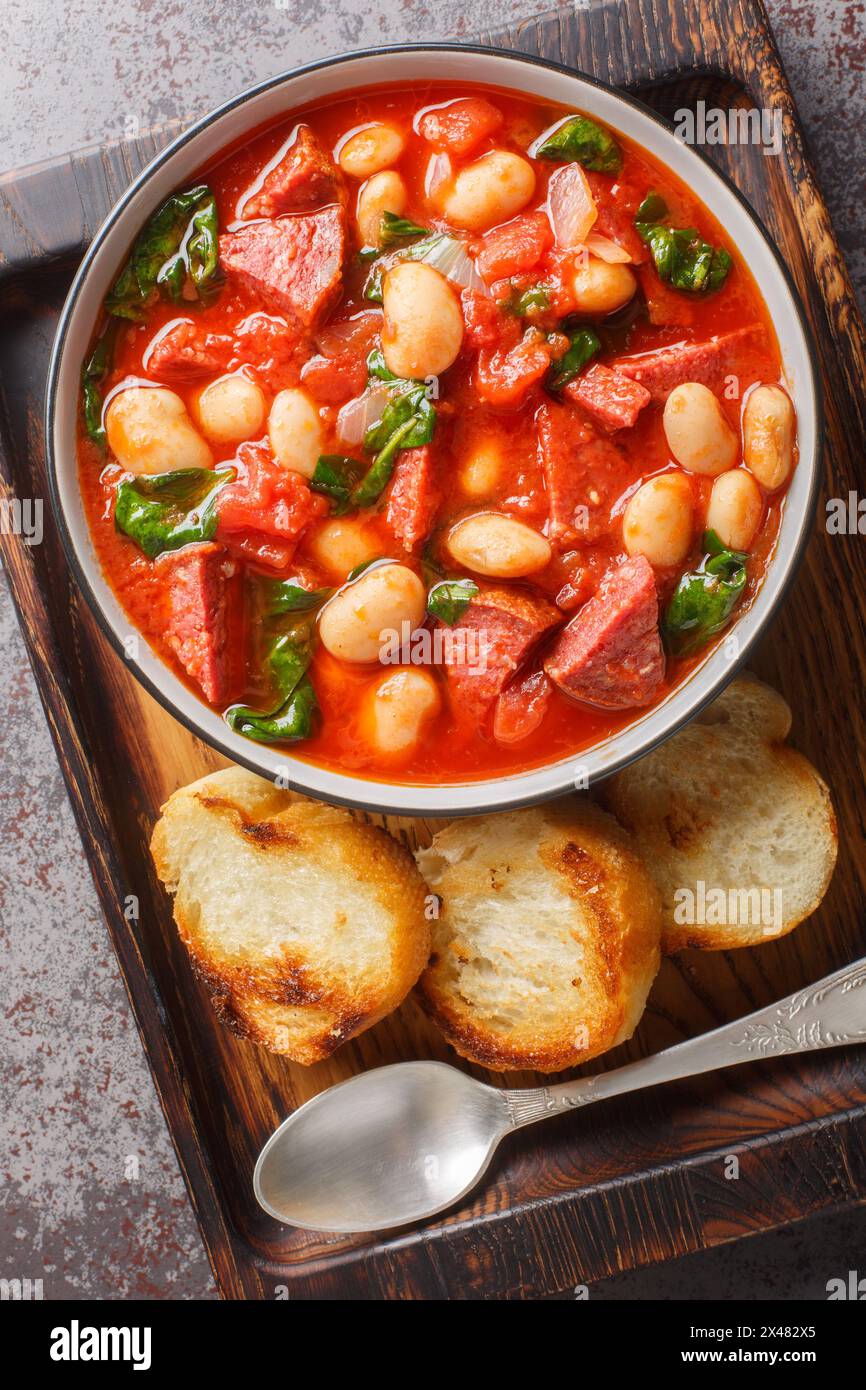 Hearty beans stew with sausages, spinach and spices in tomato sauce ...