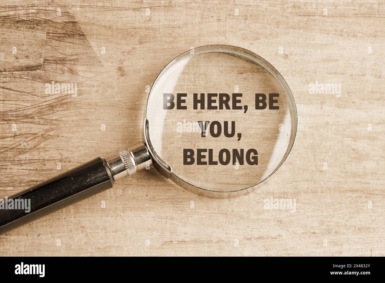BE HERE, BE YOU, BELONG Words written visible through a magnifying ...