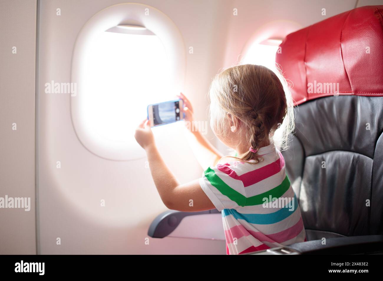 Child in airplane. Kid in air plane sitting in window seat. Flight ...
