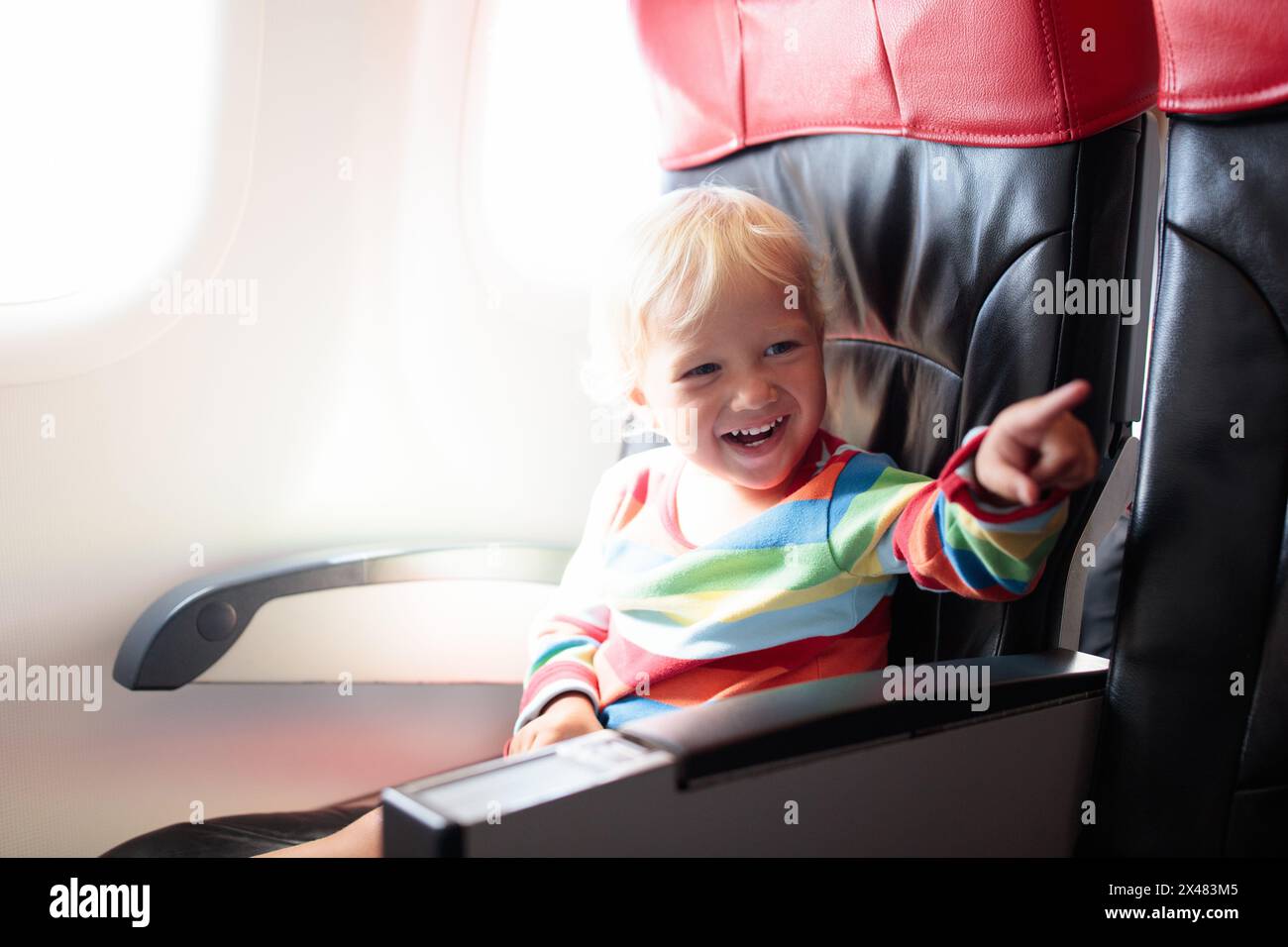 Child in airplane. Kid in air plane sitting in window seat. Flight ...