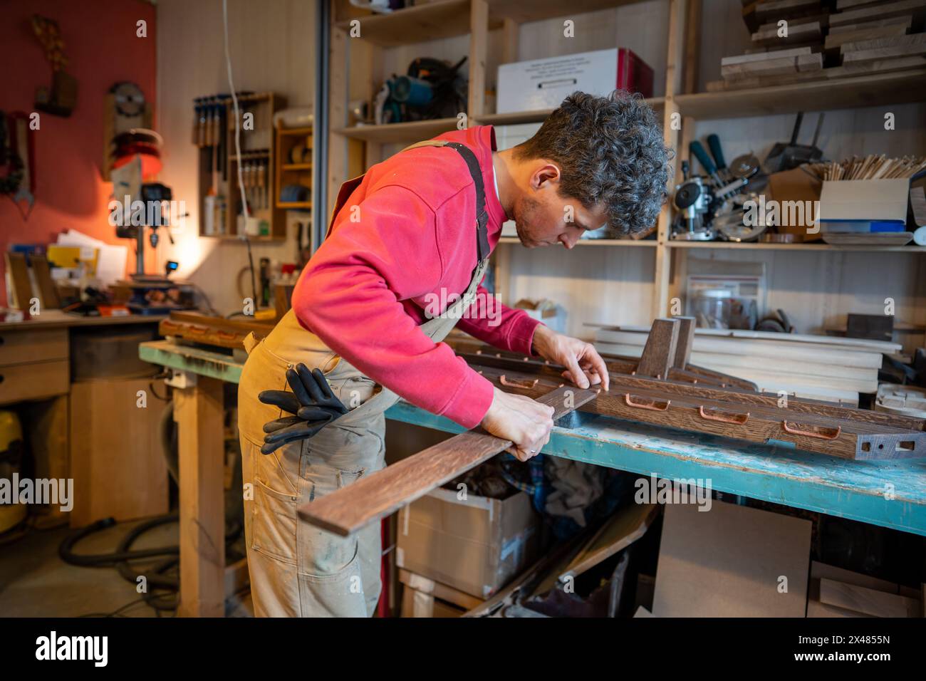 Focused man carpenter work with slatted bed base check strength ...