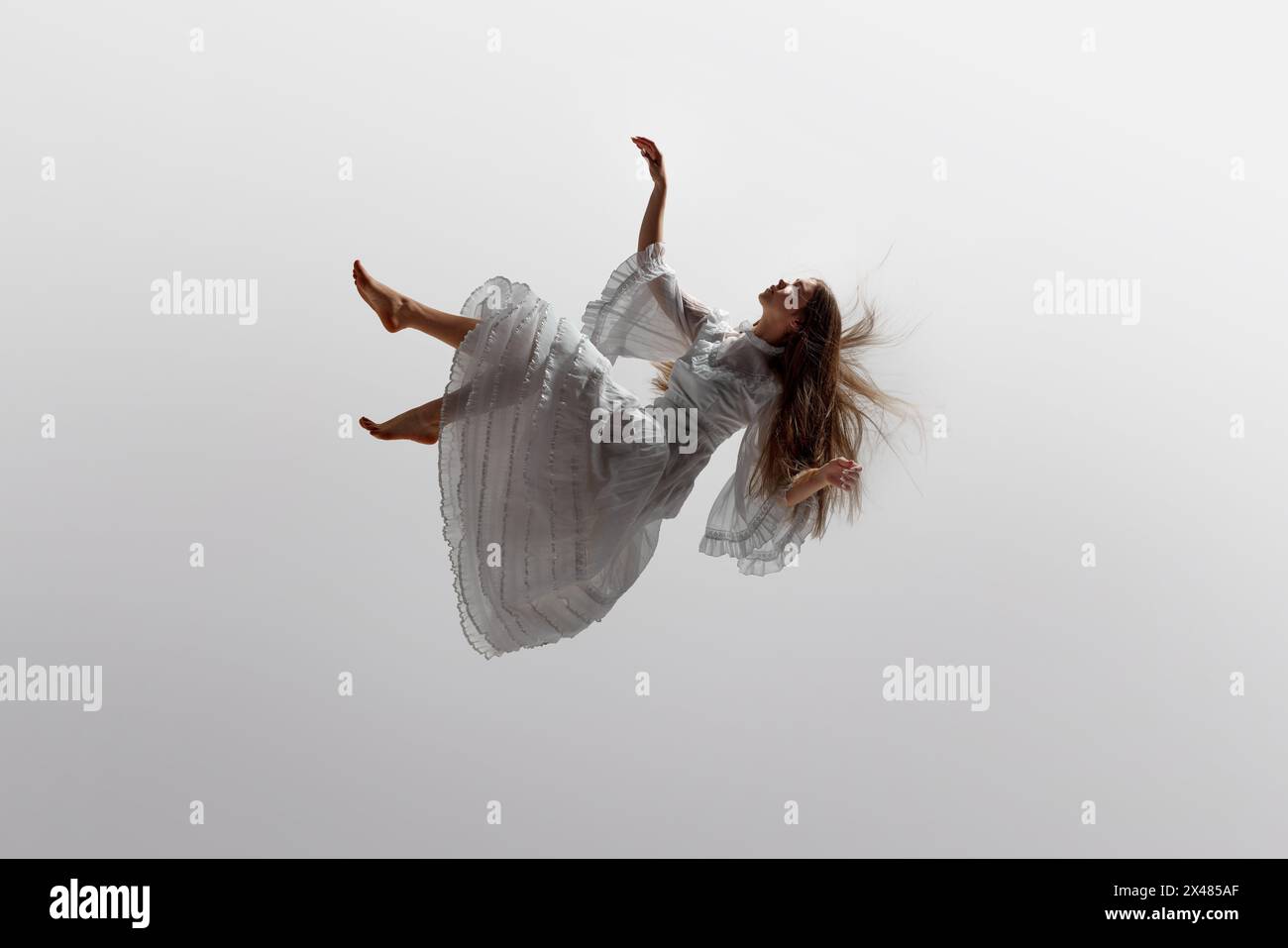 Woman in white ruffled dress floats effortlessly in moment of graceful ...