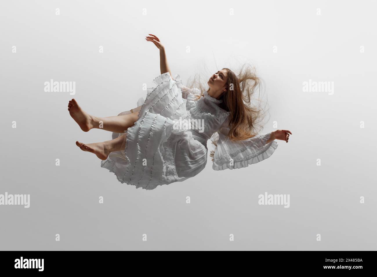 Young woman, dressed in elegant white dress with delicate ruffles ...