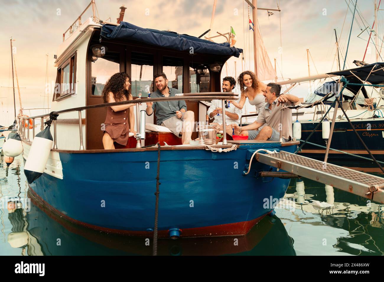 Group of friends - enjoying drinks and conversation on yacht at sunset ...