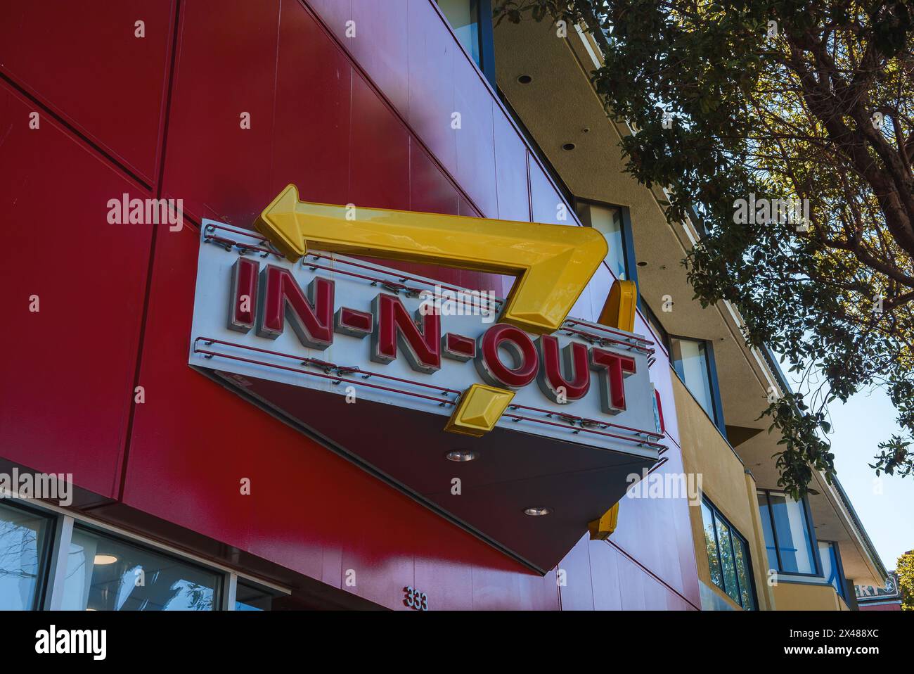 Iconic In N Out Burger sign, yellow arrow and name against red wall in ...