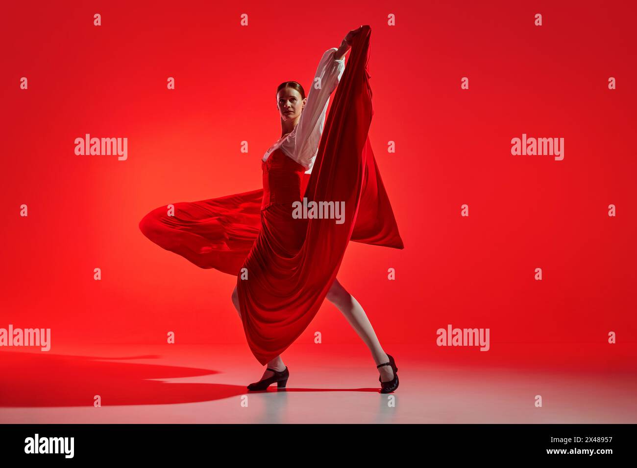 Female artistic flamenco dancer showing passion against striking red ...