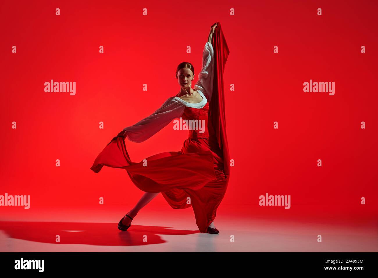 Female artistic flamenco dancer showing passion against striking red ...