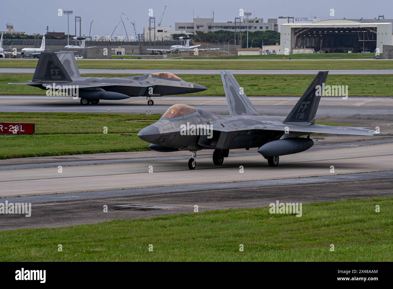 U.S. F-22A Raptors assigned to the 27th Fighter Squadron taxi away from the runway at Kadena Air ...