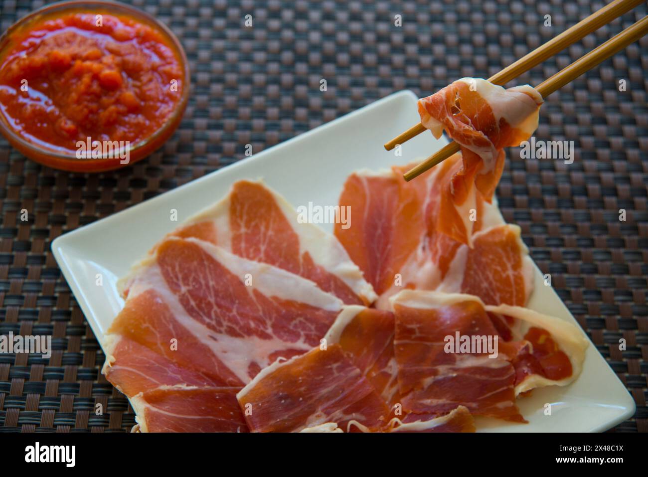 Iberian ham eaten with Chinese chopsticks Stock Photo - Alamy