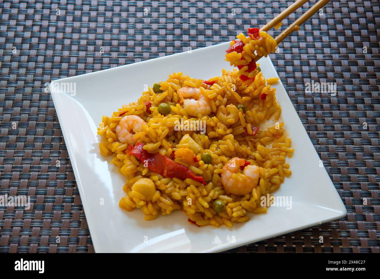 Paella valenciana eaten with Chinese chopsticks Stock Photo - Alamy
