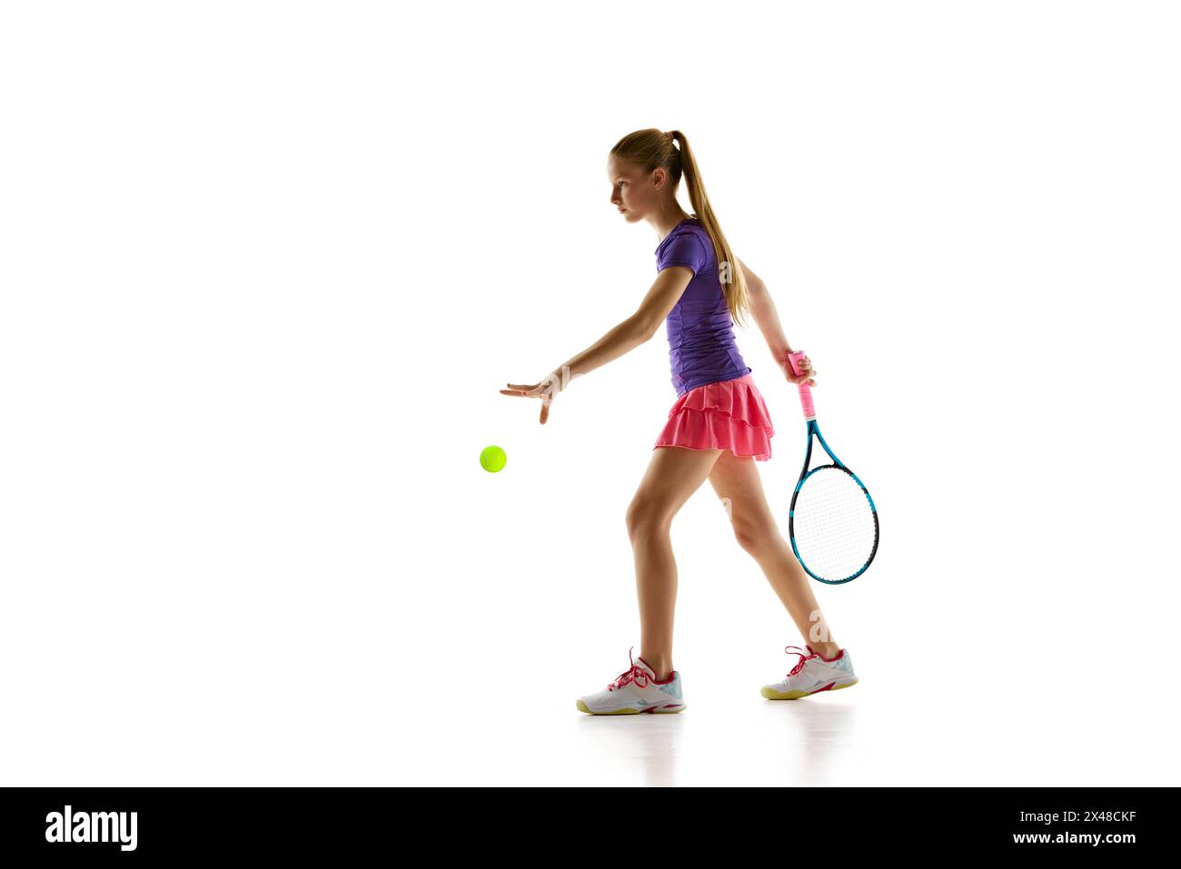 Athletic teen girl, tennis player in vibrant uniform tossing ball to ...