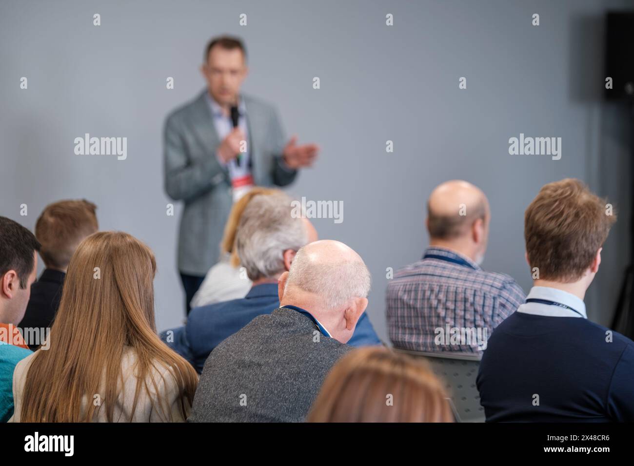 Dynamic business speaker addresses an attentive audience in a well-lit ...