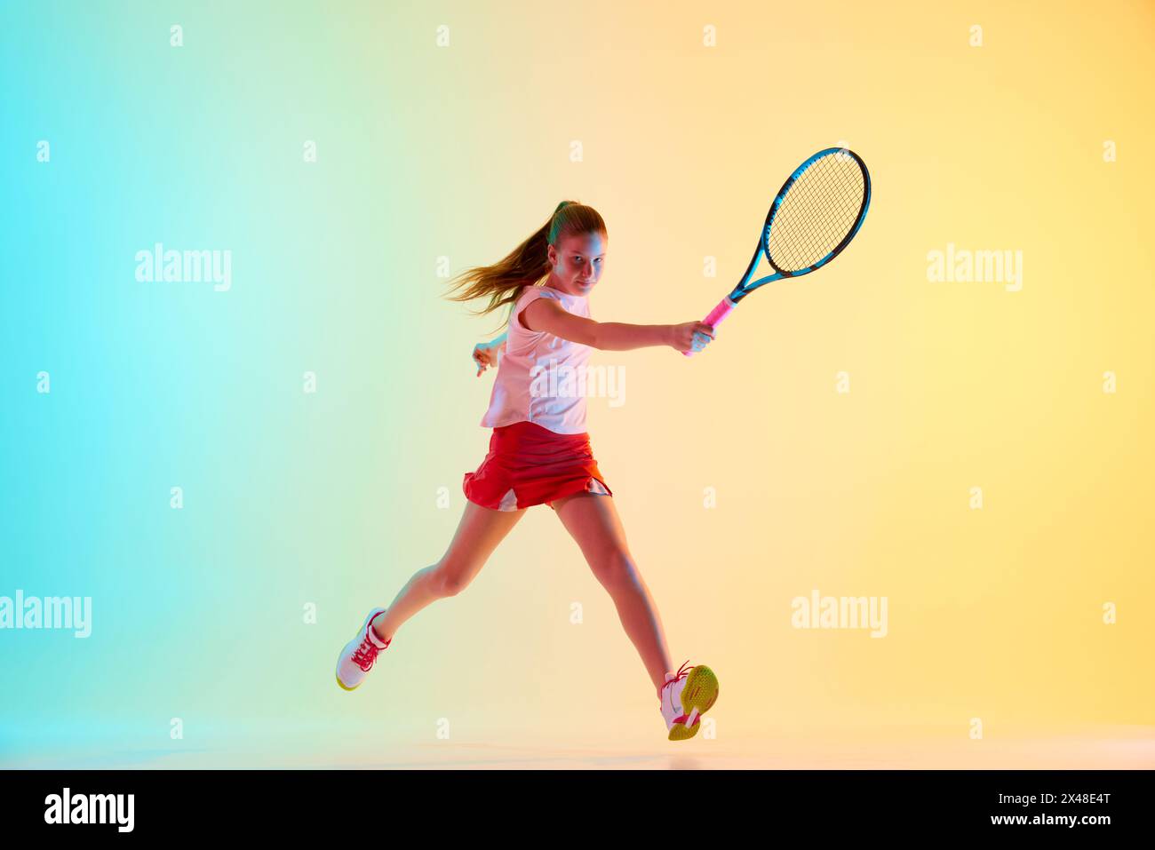 Young tennis player leaps into action , her racket poised to strike a ...