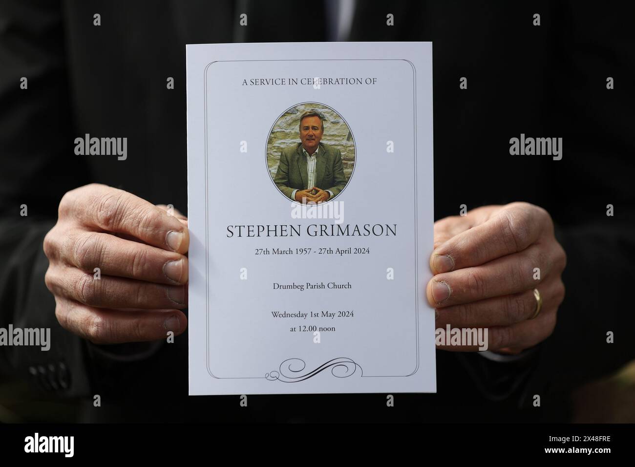 A mourner holds the order of service for the the funeral mass of former ...
