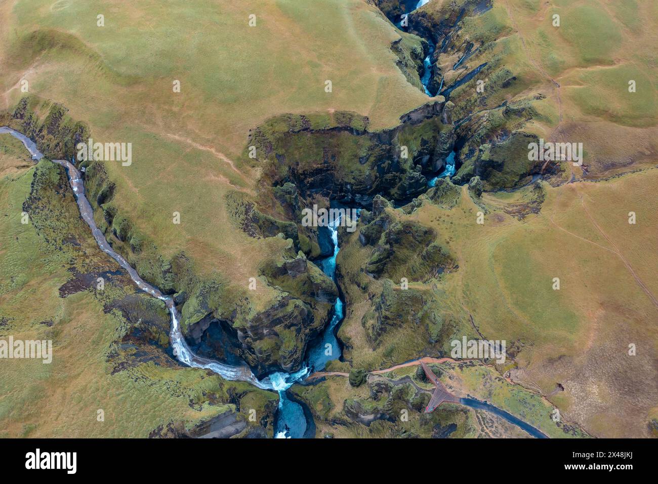 Between the hills in Iceland flows winding blue river, branch of ...