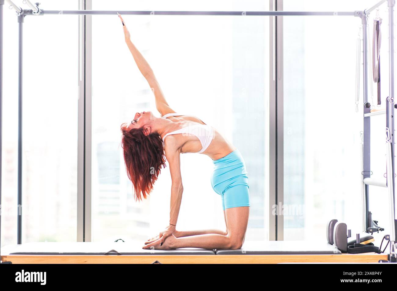 Beautiful woman performing pilates over white background with reverse ...
