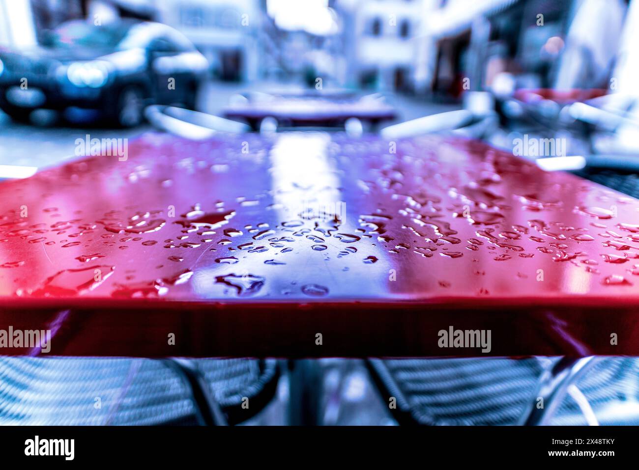 Closeup of wet red table of a restaurant or bistro on the street, after ...
