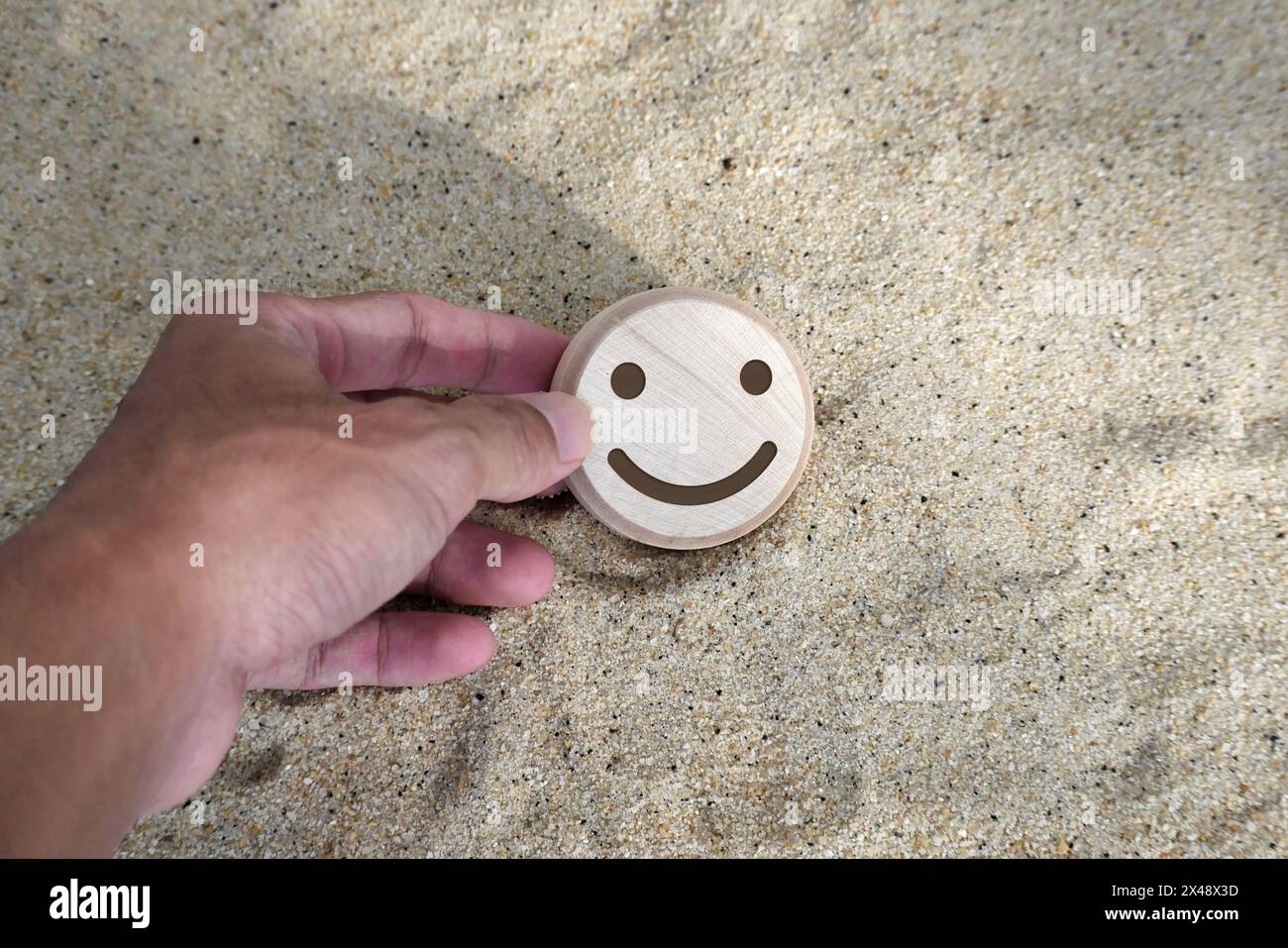wooden smiley faces on the sand. concept for Service rating ...