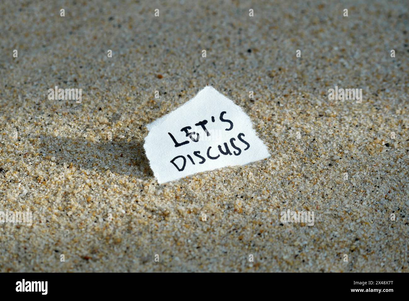 Let's Discuss handwritten text on the sand background Stock Photo - Alamy