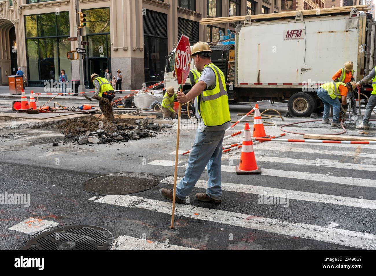 Workers dig a hole in the middle of the West 26th Street and Fifth ...