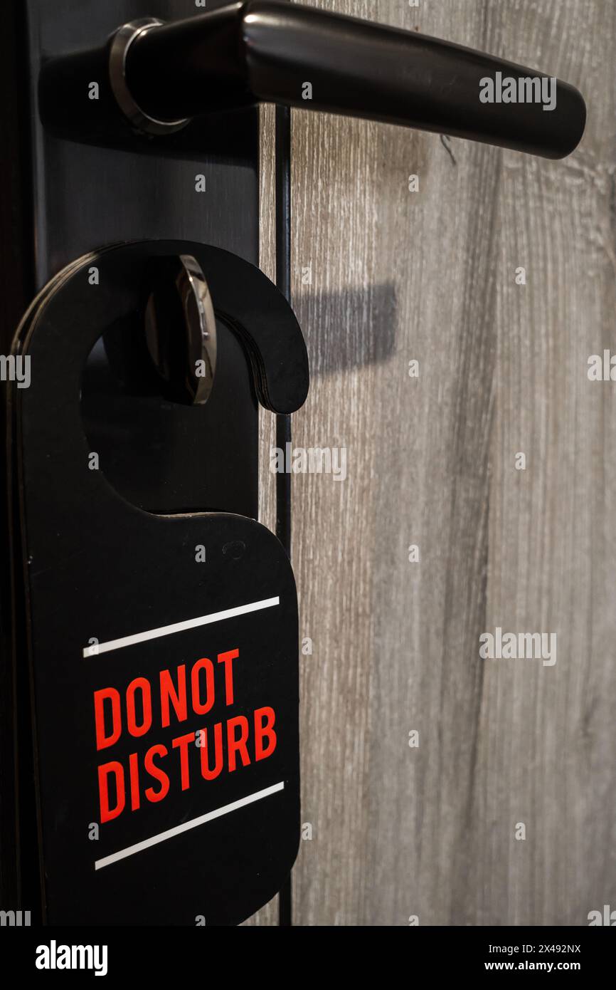 Black do not disturb sign with red text hanging on door key at hotel ...