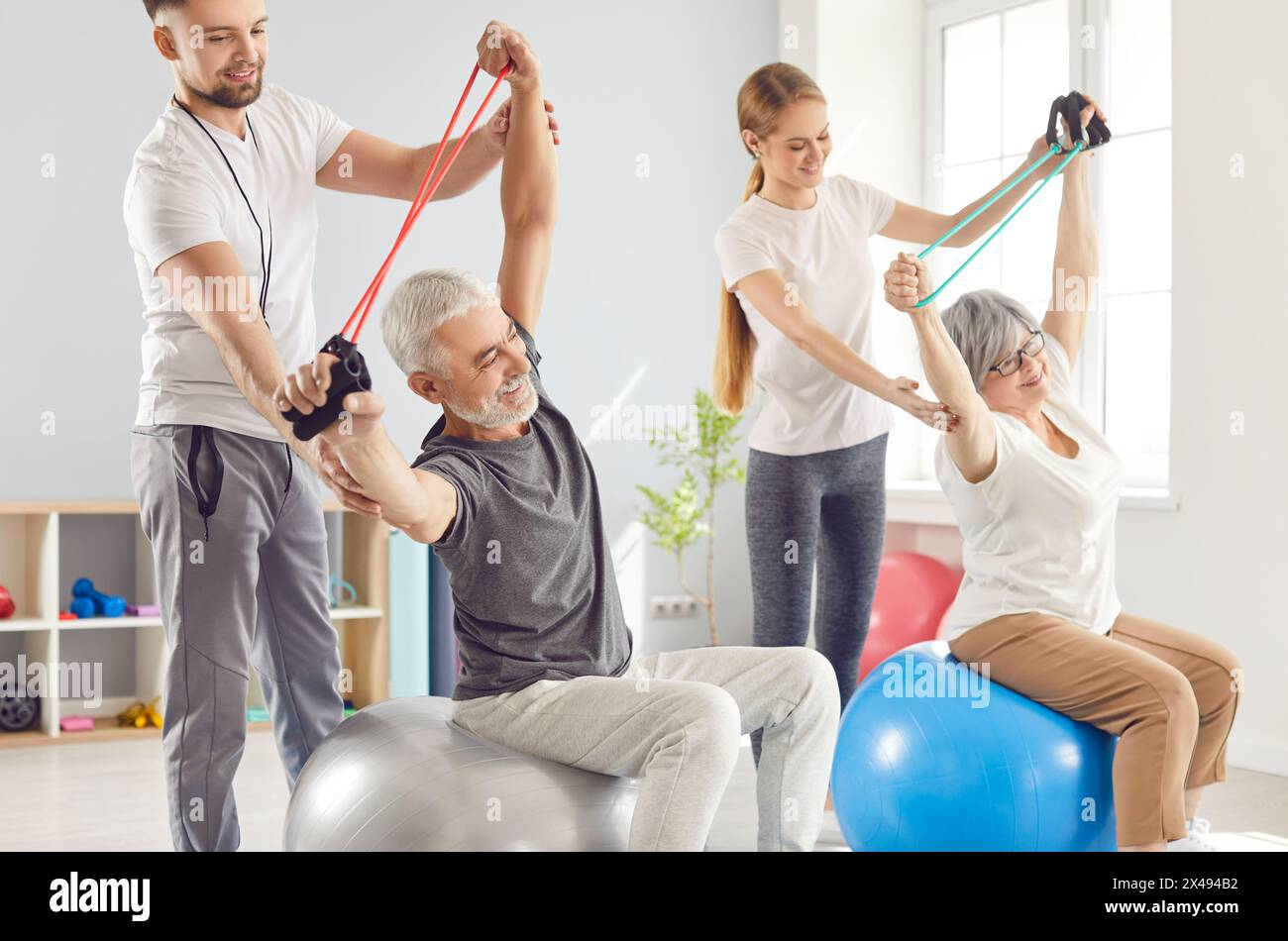 Doctor And Trainer Leading Elderly Couple In Rehabilitation Session ...
