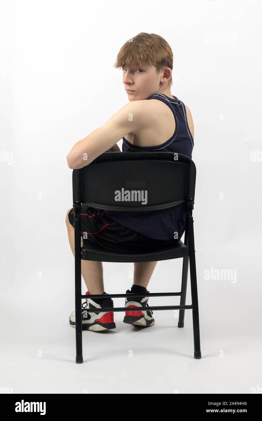A Fifteen Year Old Teenage Boy in a sleeveless top and shorts, sitting ...
