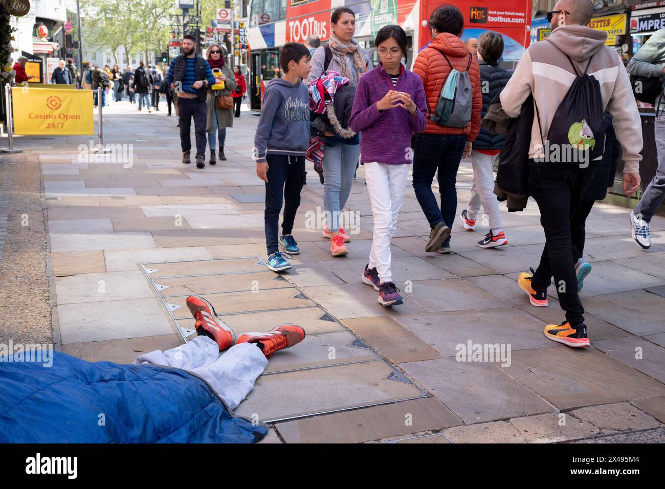 A family walk past a homeless person whose shoes stretch across the ...