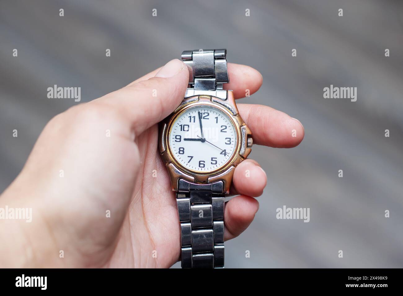 The person is wearing an analog watch on their wrist, displaying the ...