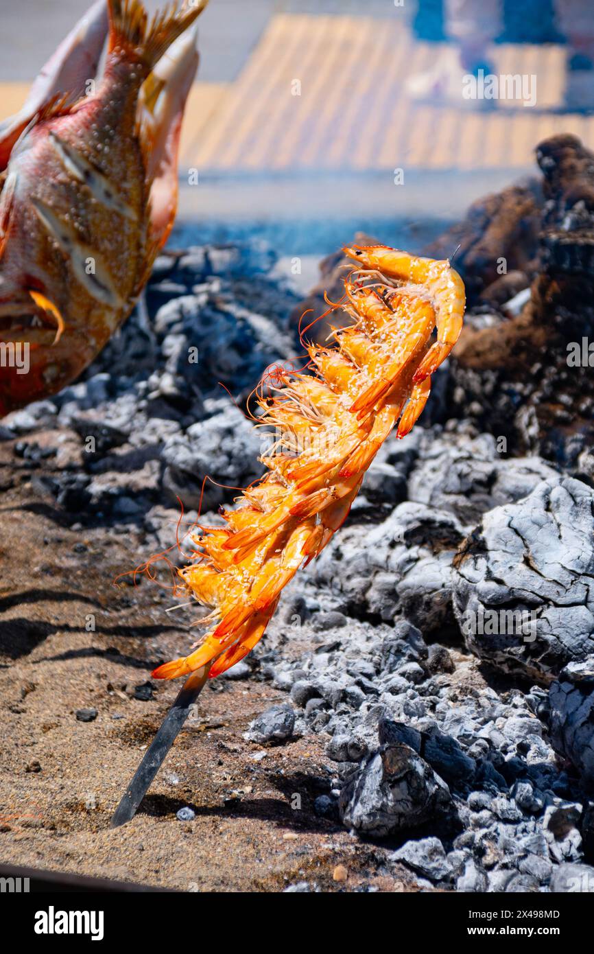 Skewers of octopus, sea bream, shrimp and sardines, grilled over a wood ...