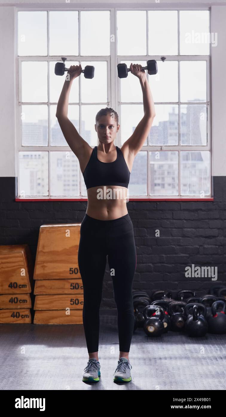 Woman, dumbbells and shoulder press in gym for workout, health and ...