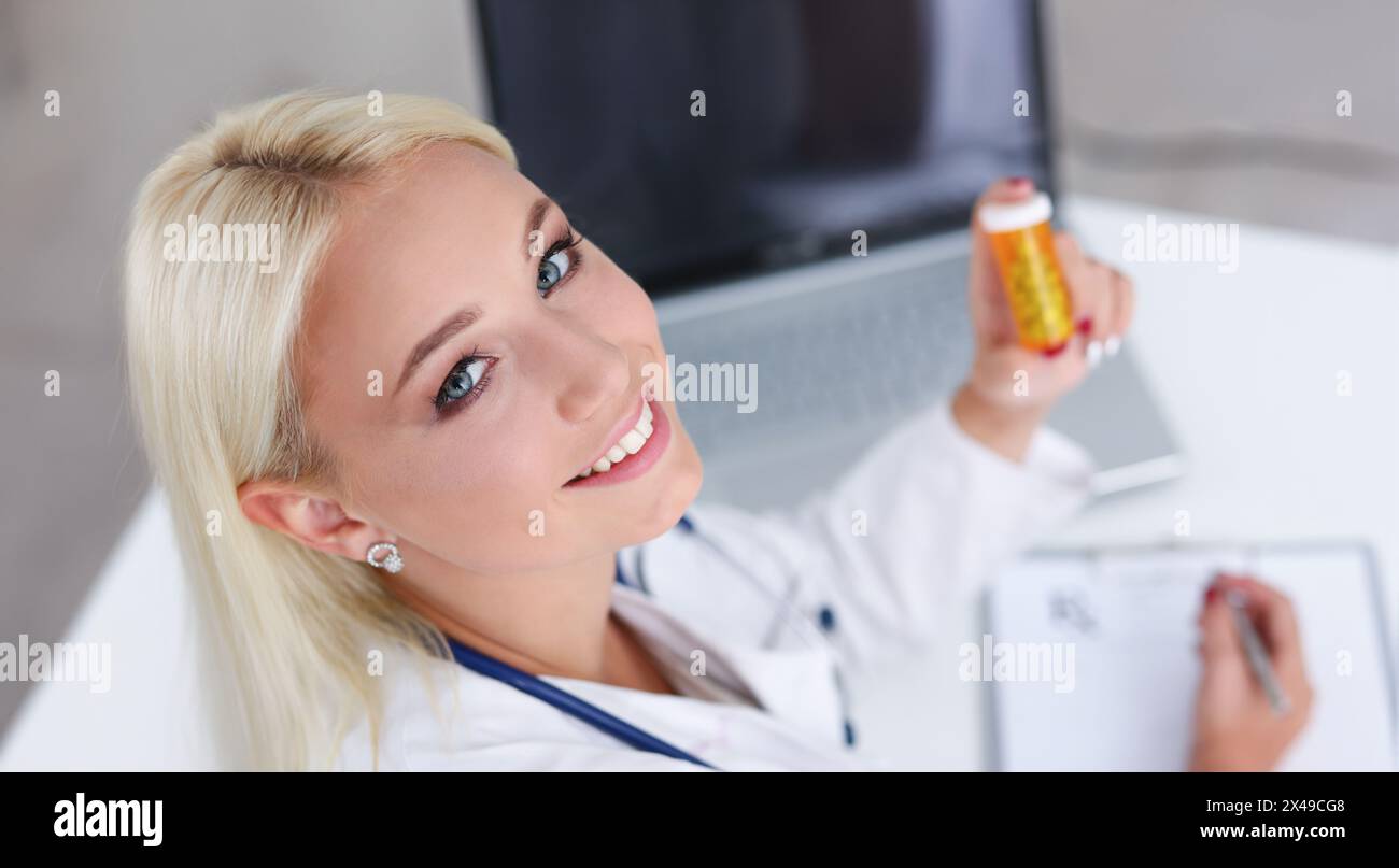 Beautiful smiling female doctor write prescription with silver pen at ...