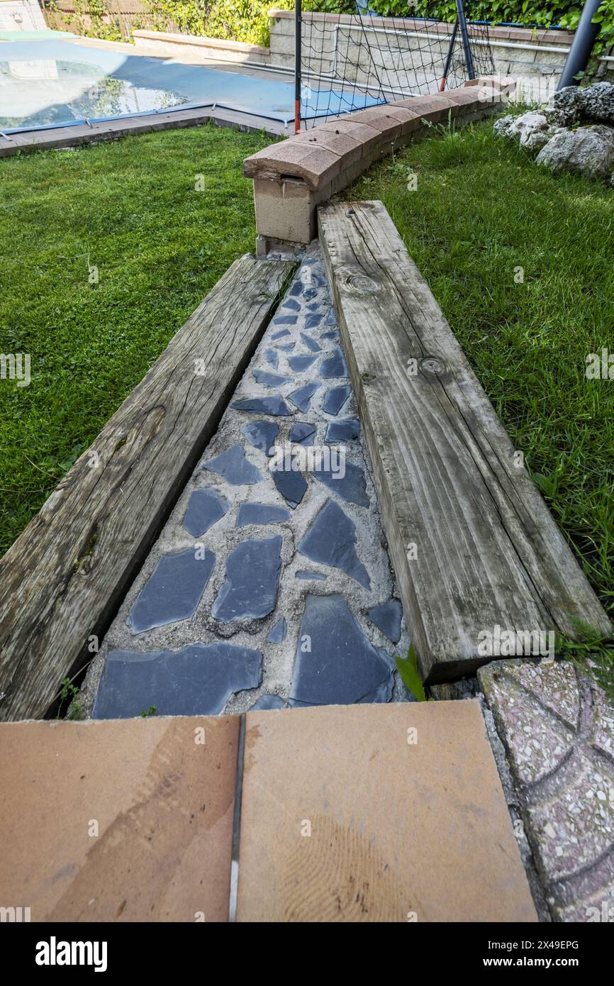 garden with a tiled path leading to a pool with wood from train ...