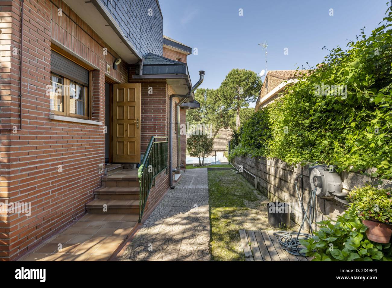 Perimeter garden with tiled path around a detached house with brick ...