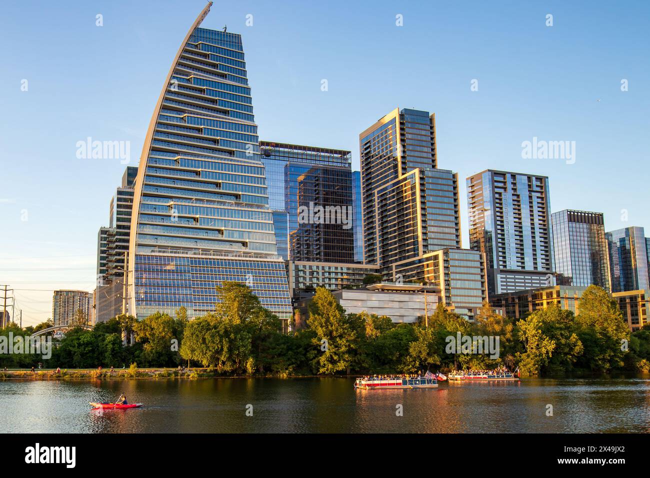 Tour boats and kayaks on Lady Bird Lake with the modern city of Austin ...