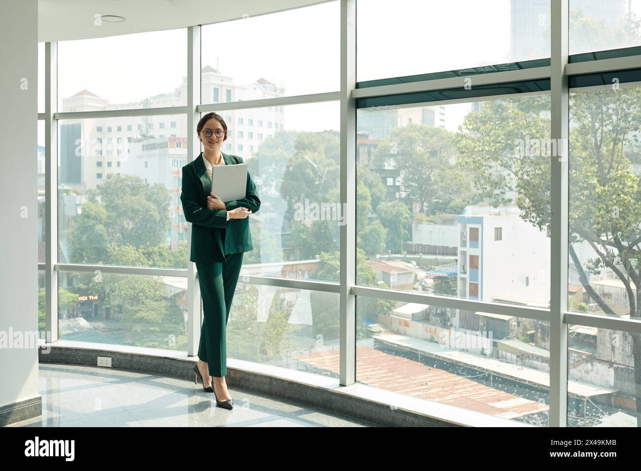 Portrait of female entrepreneur with laptop standing at panoramic ...
