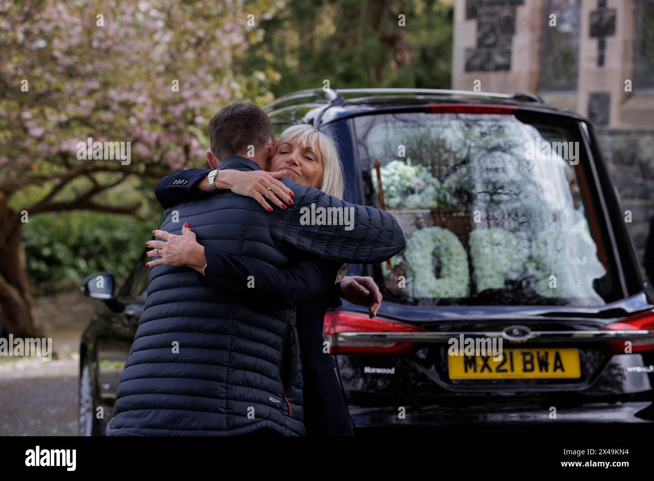 Mourners embrace each other as the hearse, carrying the coffin of ...