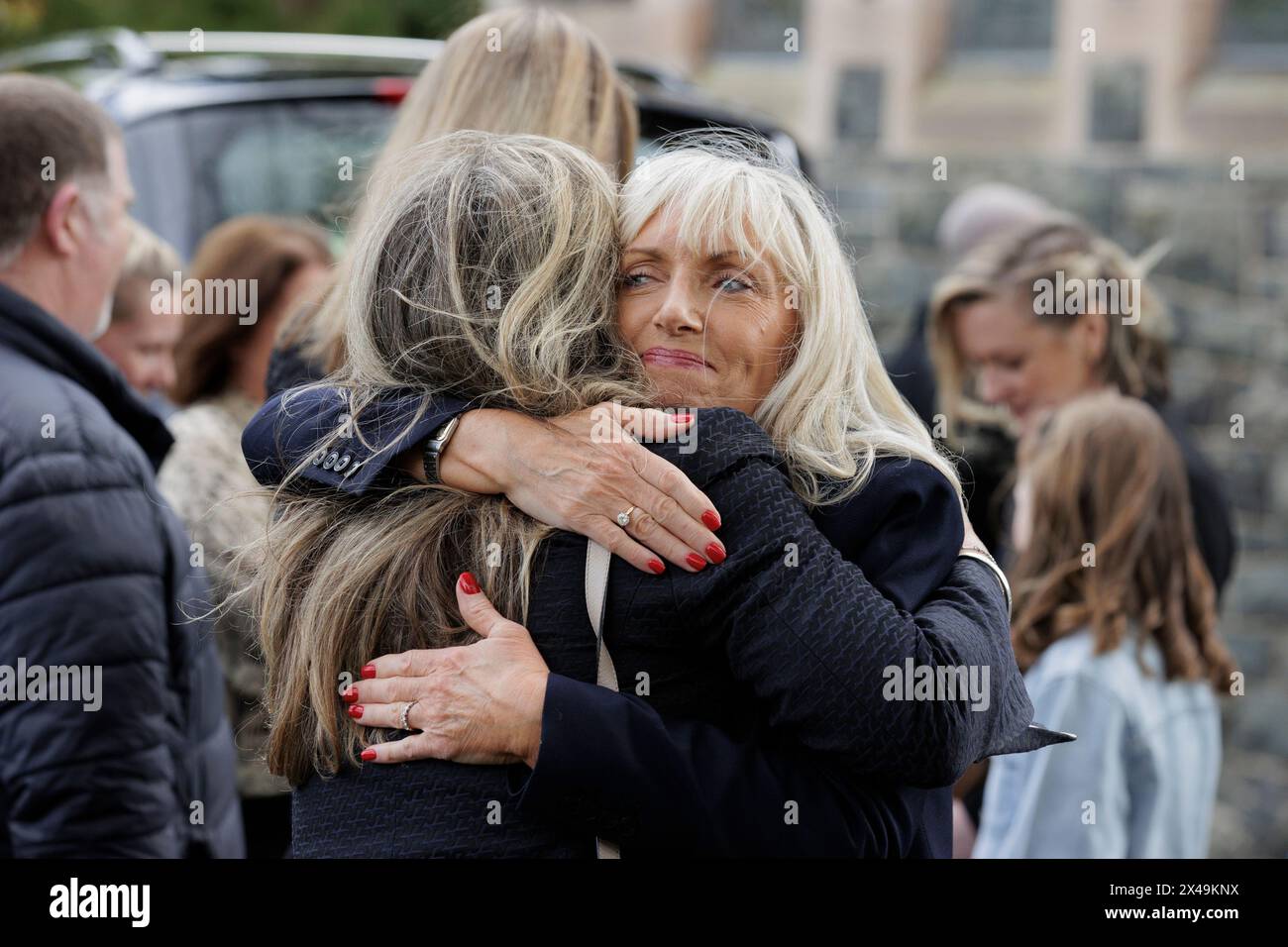 Mourners embrace each other as the hearse, carrying the coffin of ...