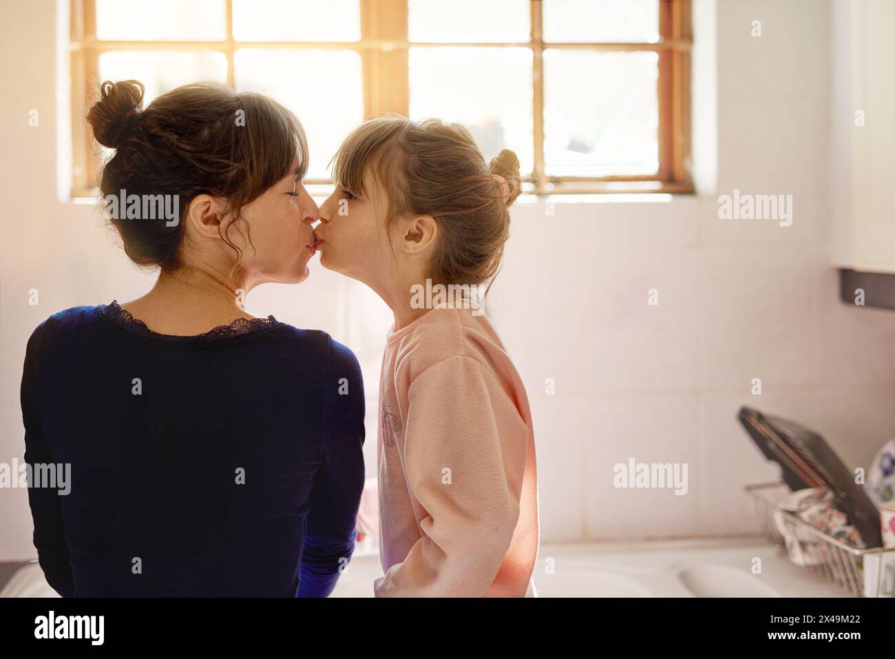 Kiss, bonding and mother with child in kitchen for housekeeping or ...