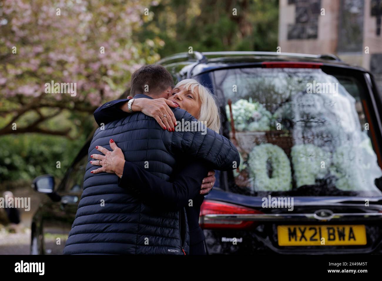 Mourners embrace each other as the hearse, carrying the coffin of ...