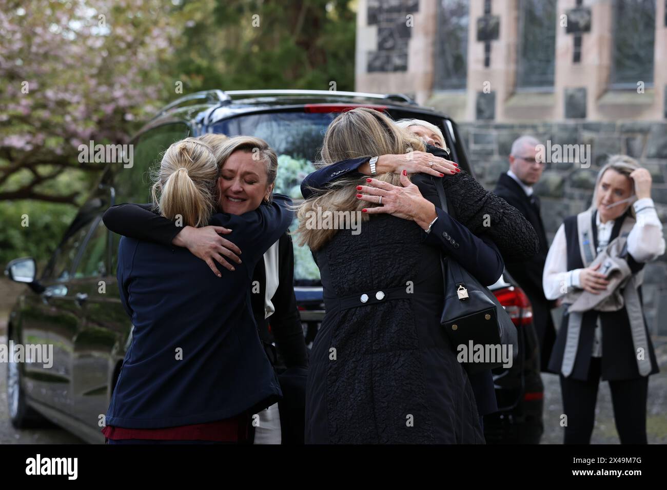 Mourners embrace each other as the hearse, carrying the coffin of ...