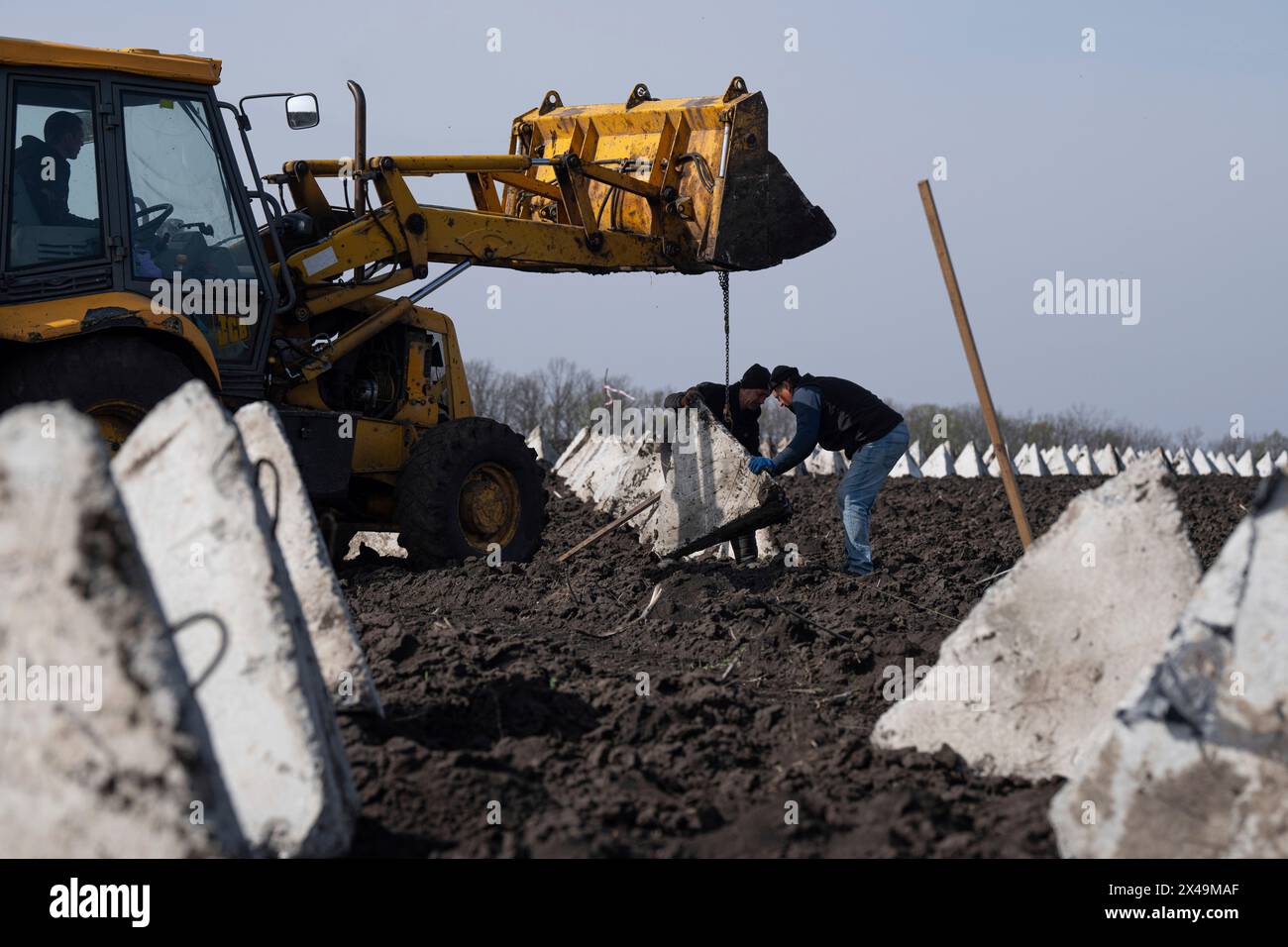 Workers install anti-tank defenses known as “dragon teeth” during ...