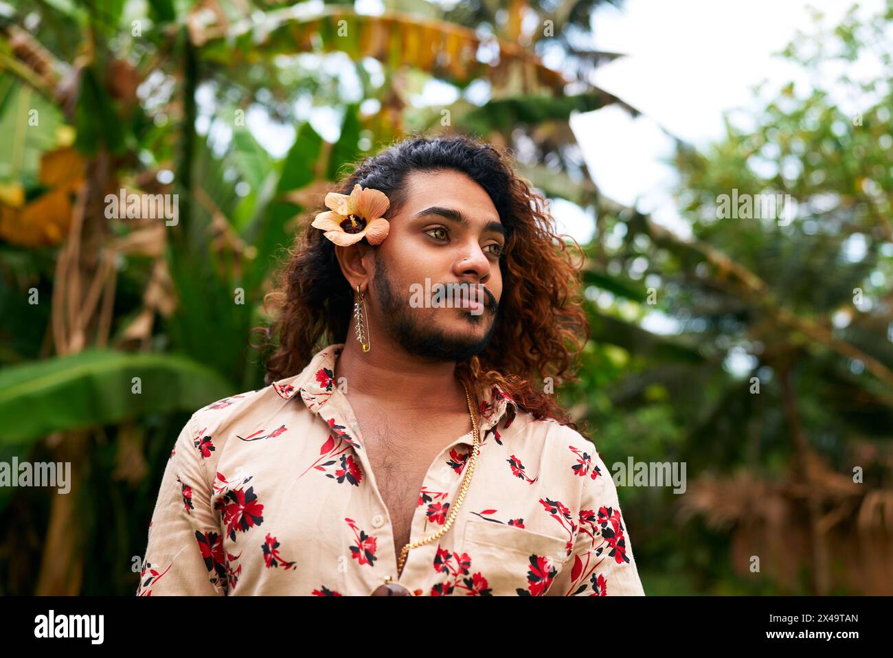 Exotic BIPOC gay man with flower in hair poses vibrant, LGBTQ pride ...